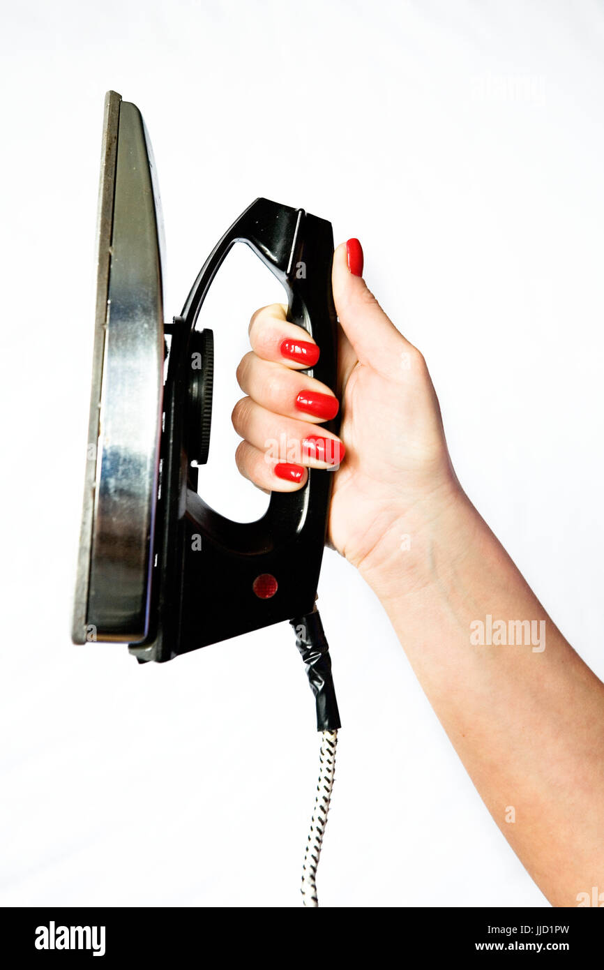 Old vintage iron in a graceful female hand with red nails on a white ...