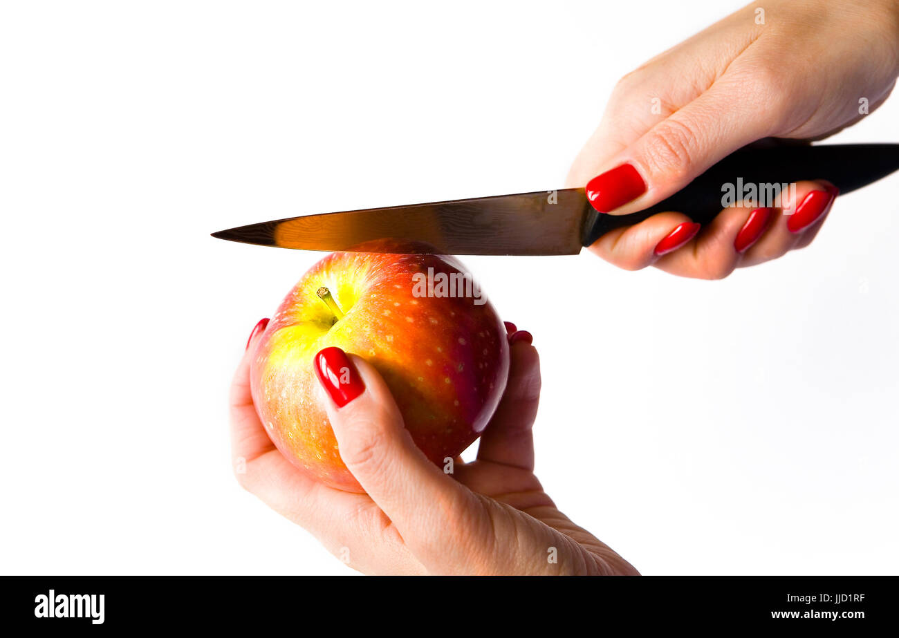 Female hands with red nails cut a ripe apple with a knife on a white ...