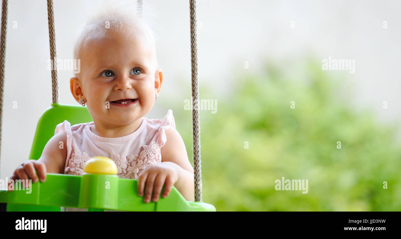 Happy baby enjoying outdoor activities and smiling while swinging Stock ...