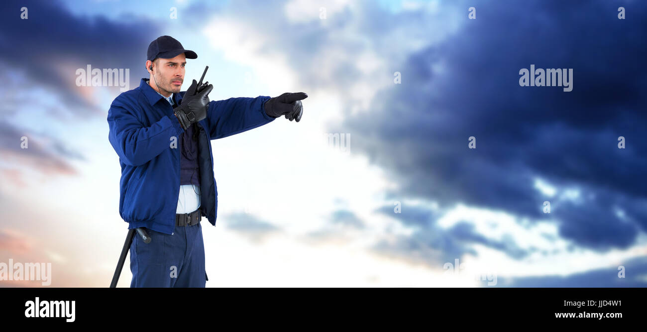 Security officer pointing away while talking on walkie talkie against ...
