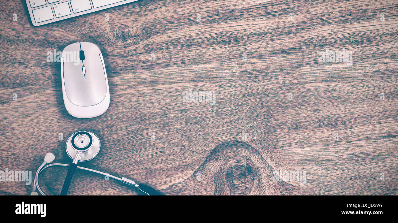 Overhead view of computer mouse and keyboard with stethoscope on wooden ...