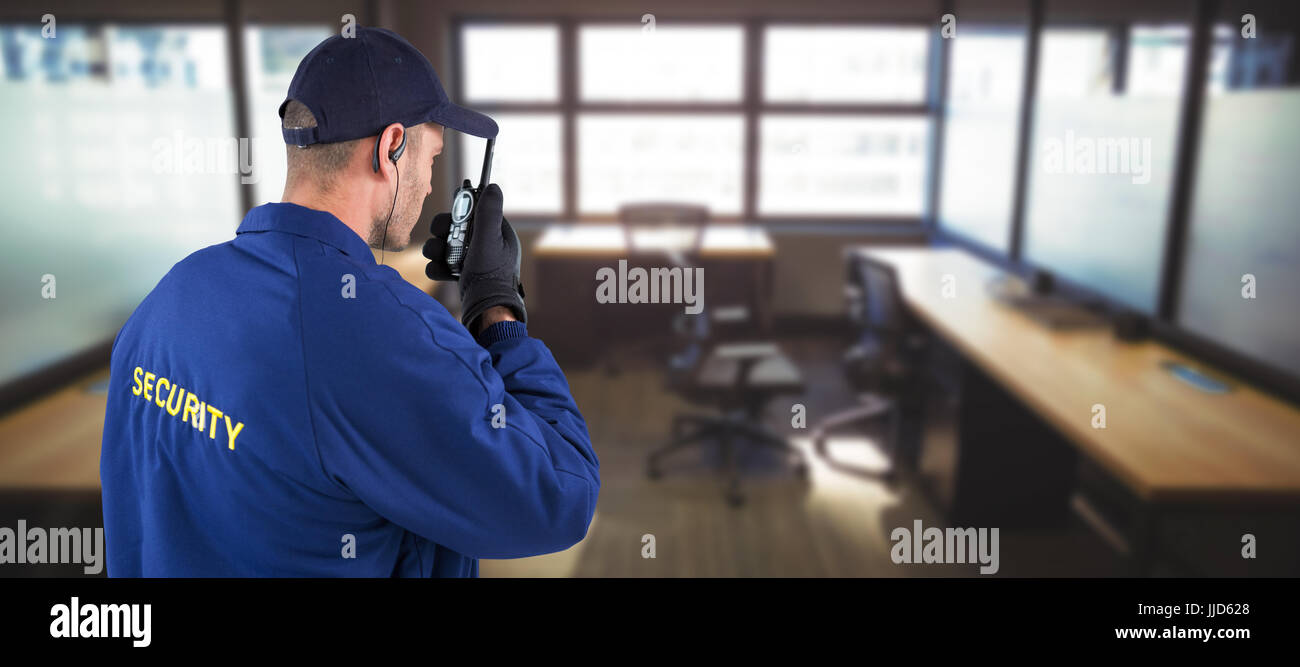 Rear view of focused security officer talking on walkie talkie against ...