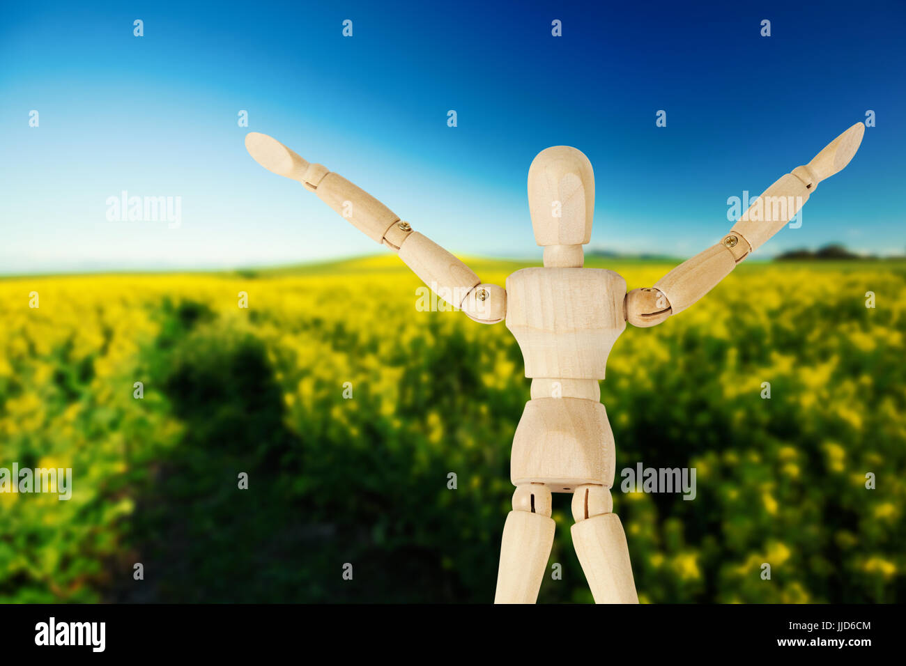 3d image of arms raised wooden figurine against yellow mustard field ...