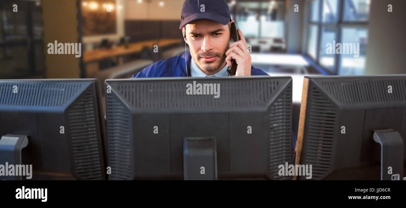 Security officer talking on phone while using computer at desk against ...
