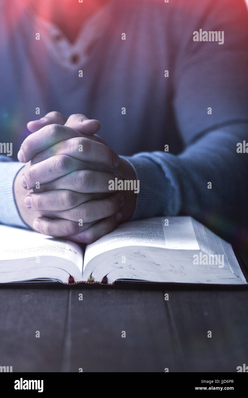 Mid section of man with bible praying at wooden desk Stock Photo - Alamy