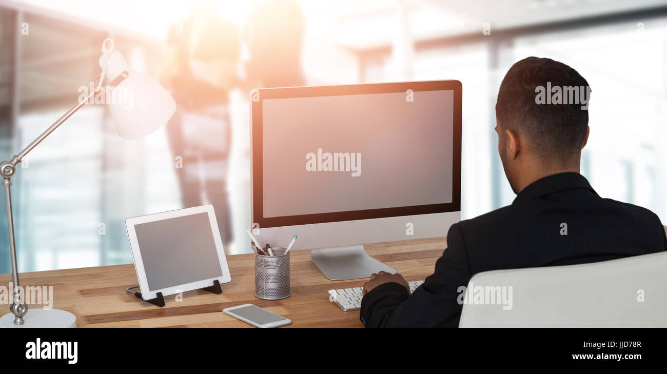 Rear view of businessman working over computer against business ...