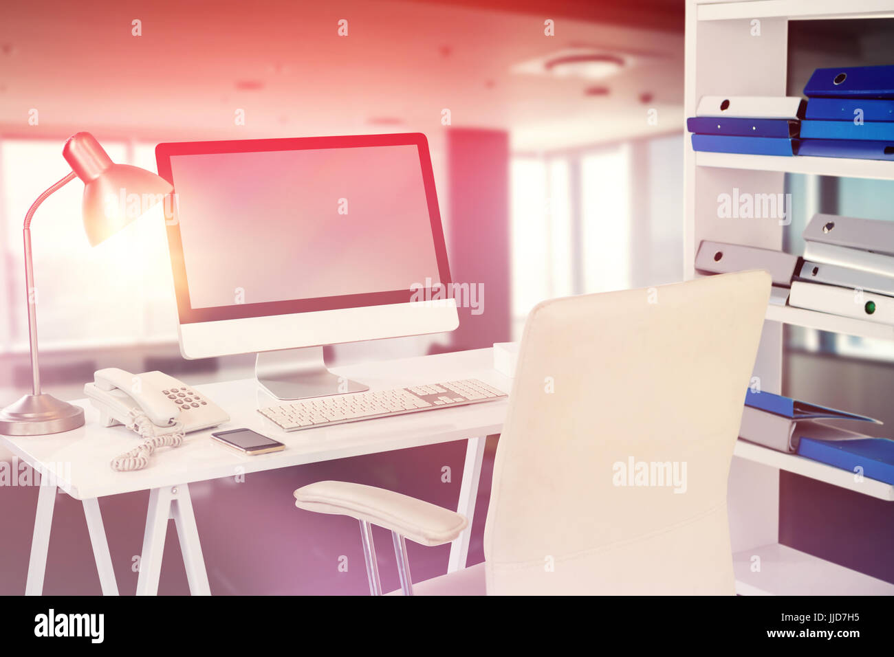 Computer with telephone and mobile phone at desk against empty chairs ...