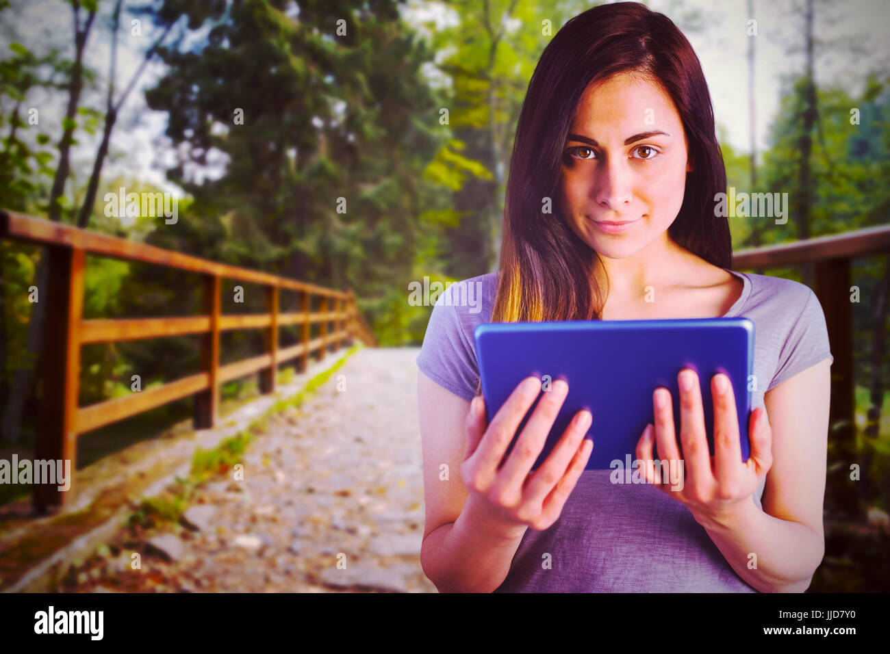 Portrait of brunette holding digital tablet against bridge with ...