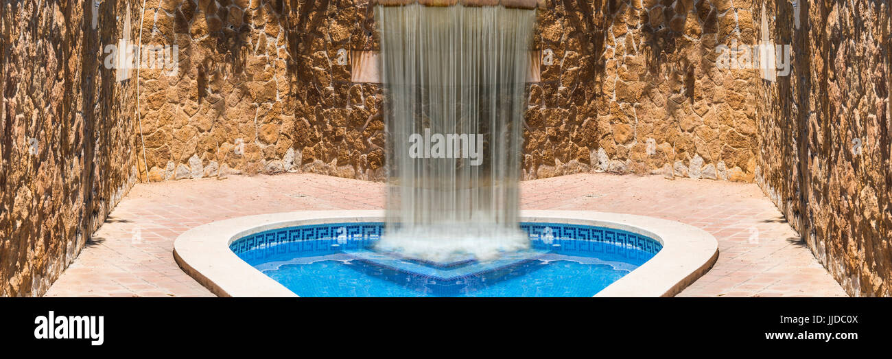 Luxury swimming pool with waterfall. In the background a mediterranean ...