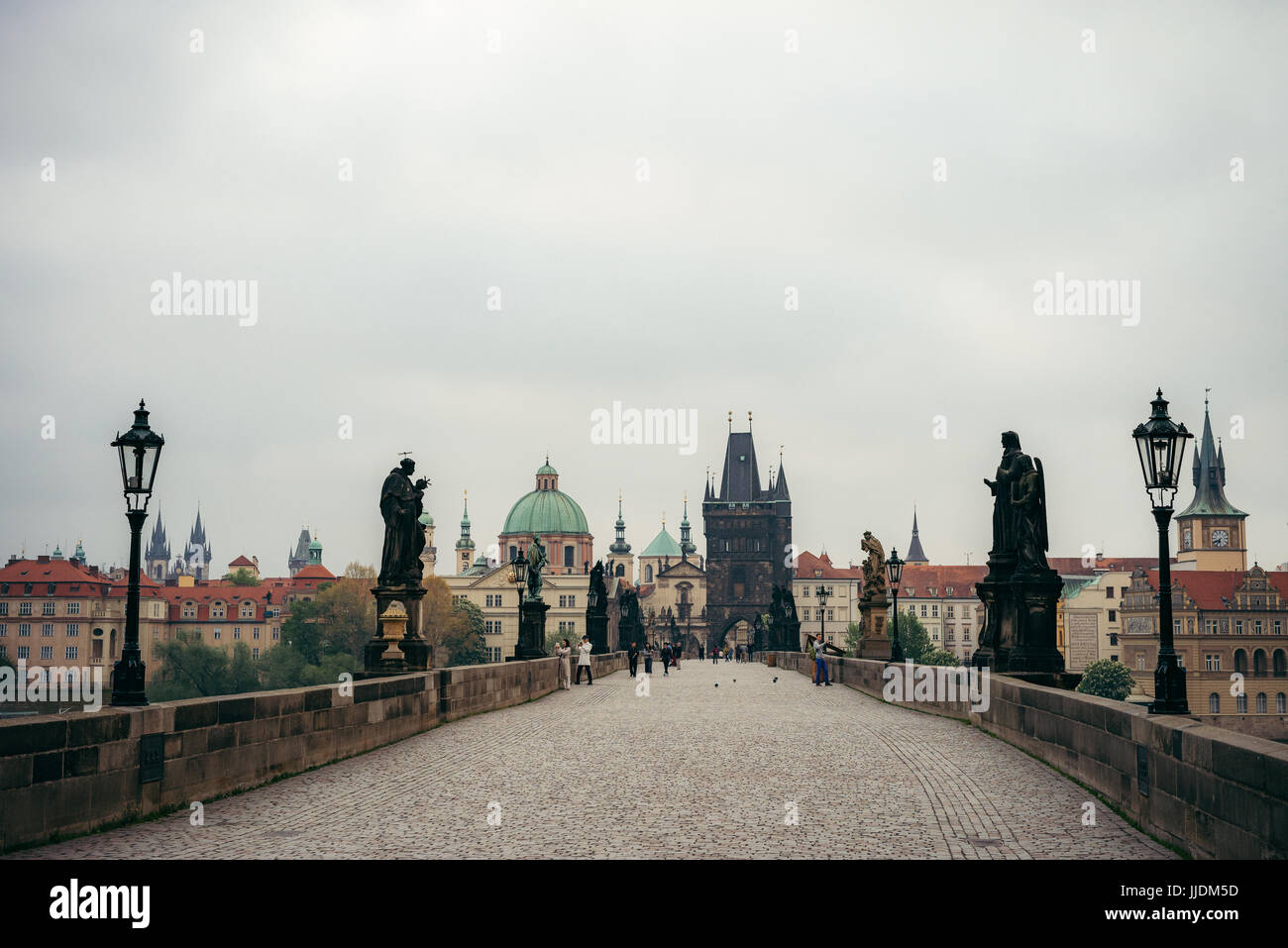 The Charles Bridge in prague is crowded with people during the cloudy ...