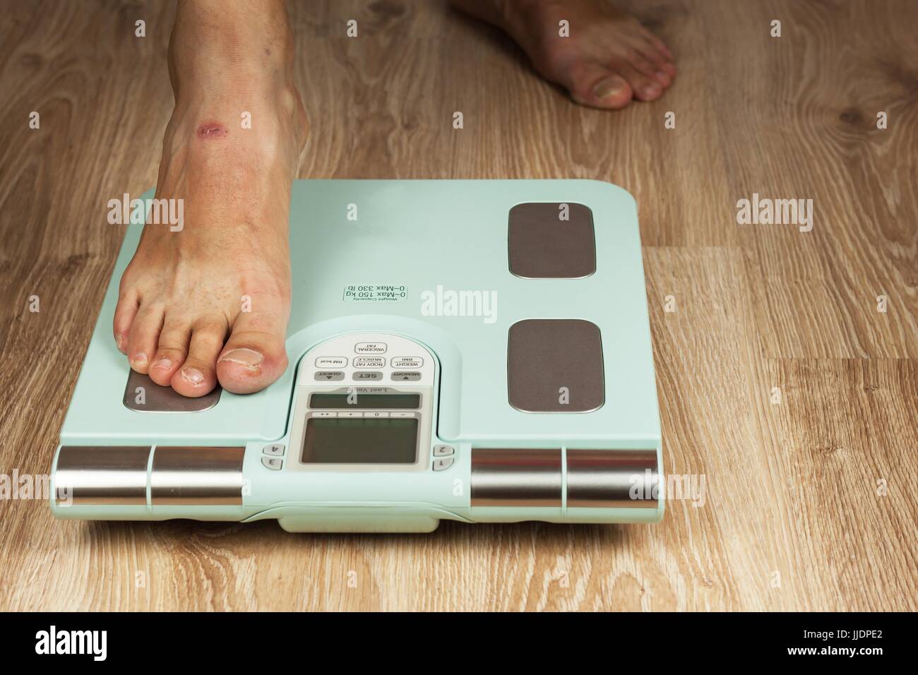The old man is standing on a modern scale. Measuring the fat content of ...