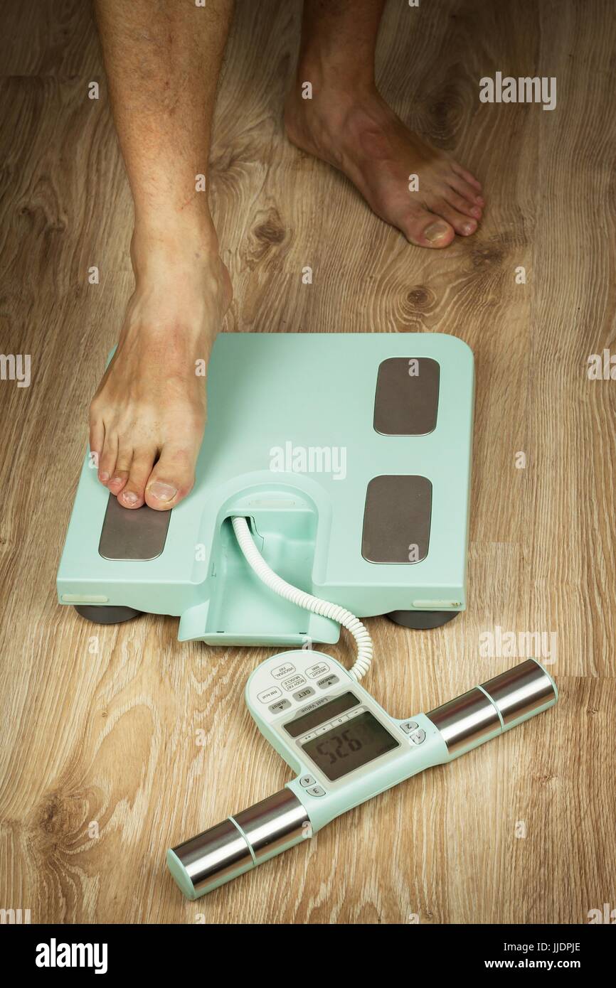 The old man is standing on a modern scale. Measuring the fat content of ...