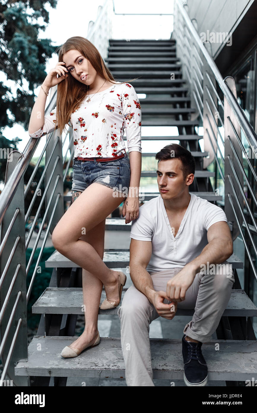 Portrait of young modern couple in love, posing outdoors in city street ...