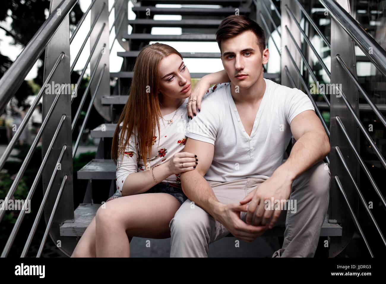 Portrait of young modern couple in love, posing outdoors in city street ...