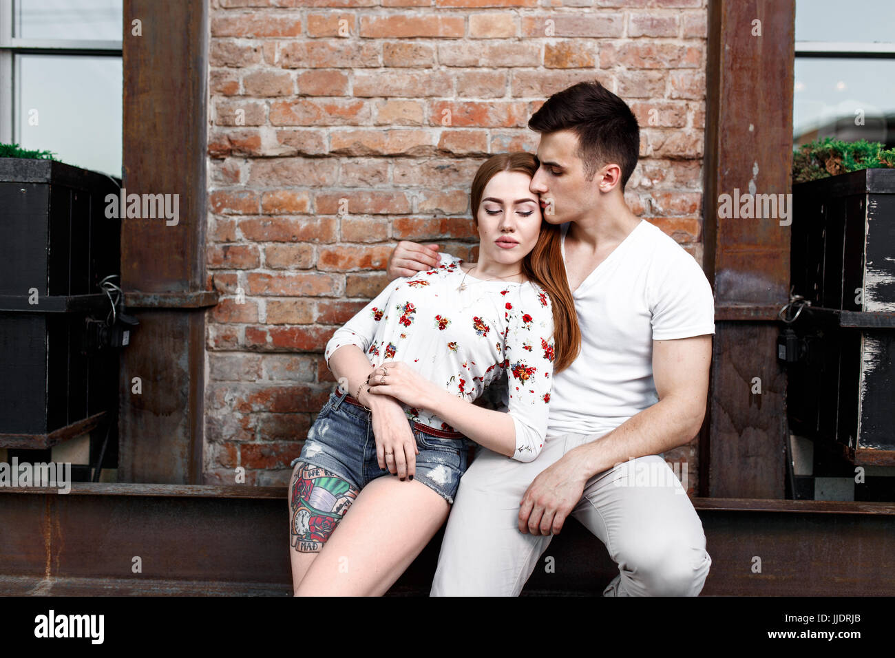 Portrait of young modern couple in love, posing outdoors in city street ...