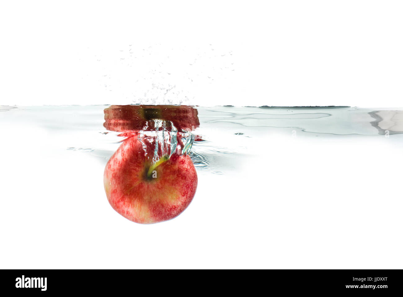 Red apple dropped into the water with water splash on a white ...