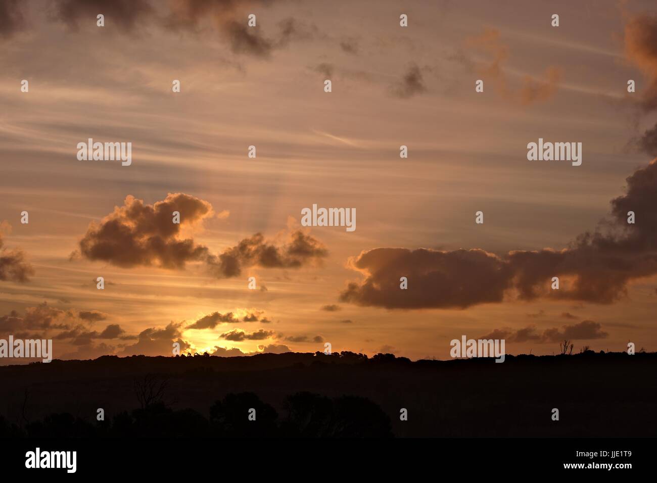 Setting sun in cloudy sky Stock Photo - Alamy
