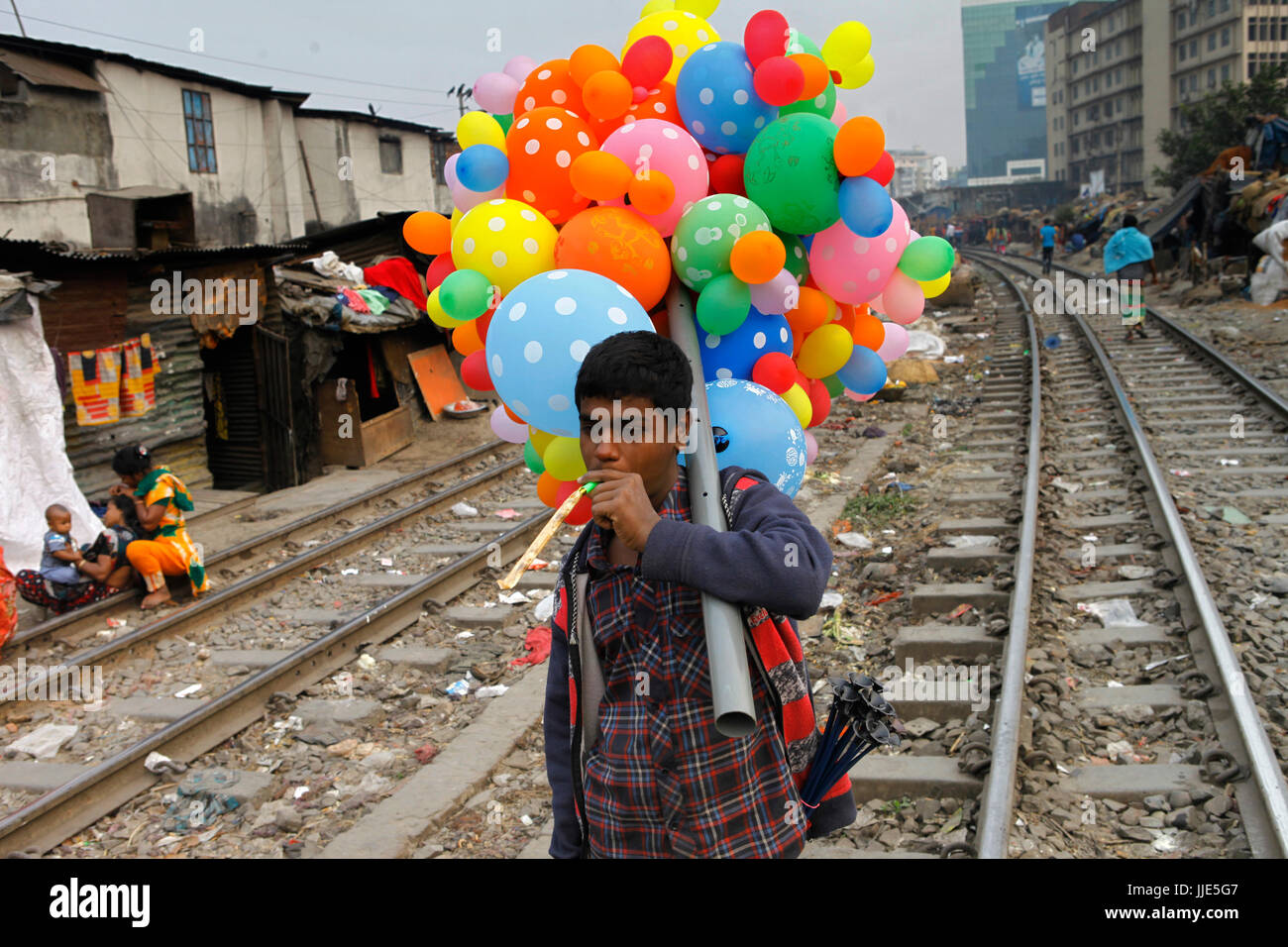 DHAKA, BANGLADESH – January 19: A balloon seller walks on a railway ...