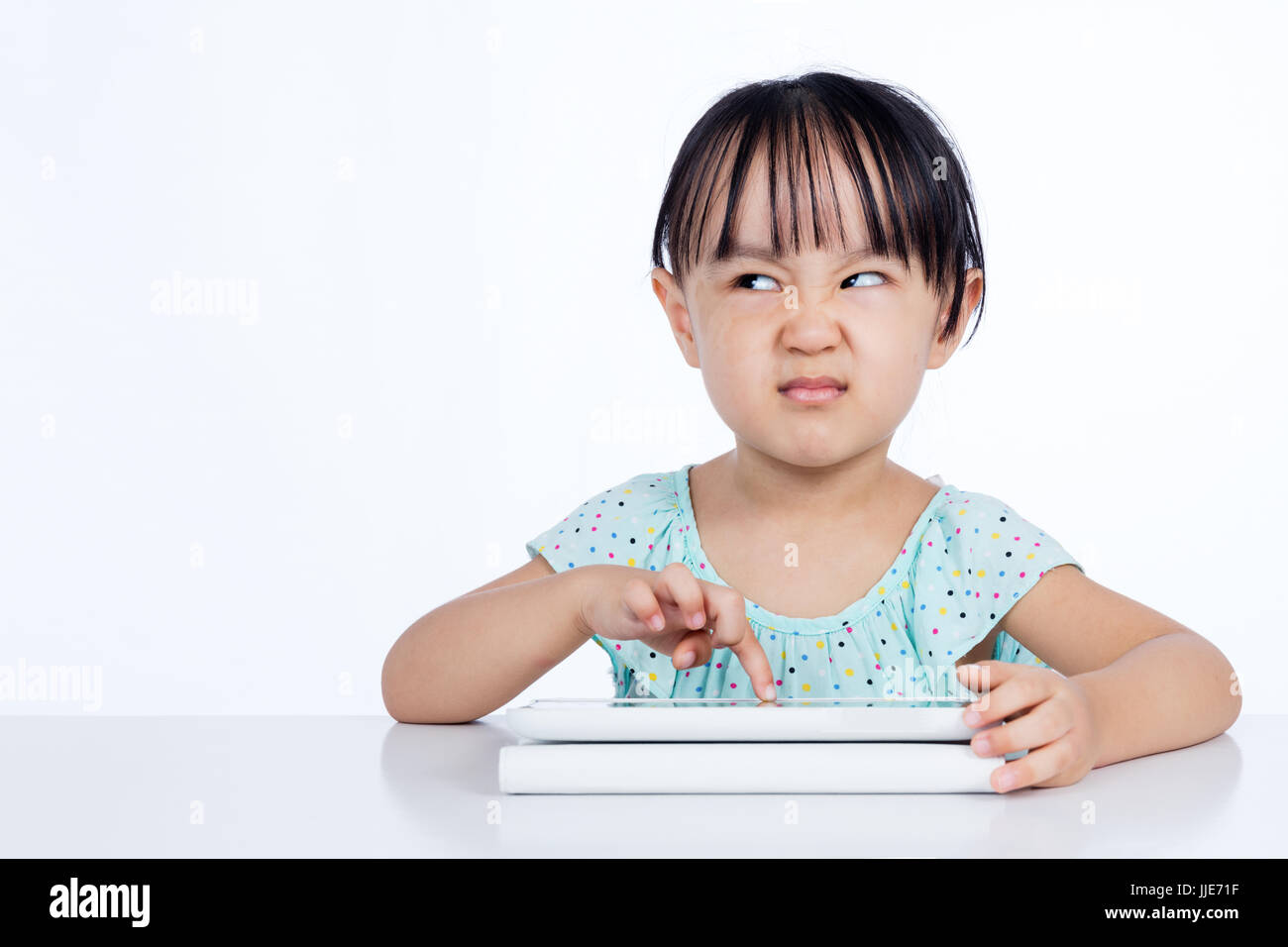 Asian Chinese little girl playing with tablet computer in isolated ...