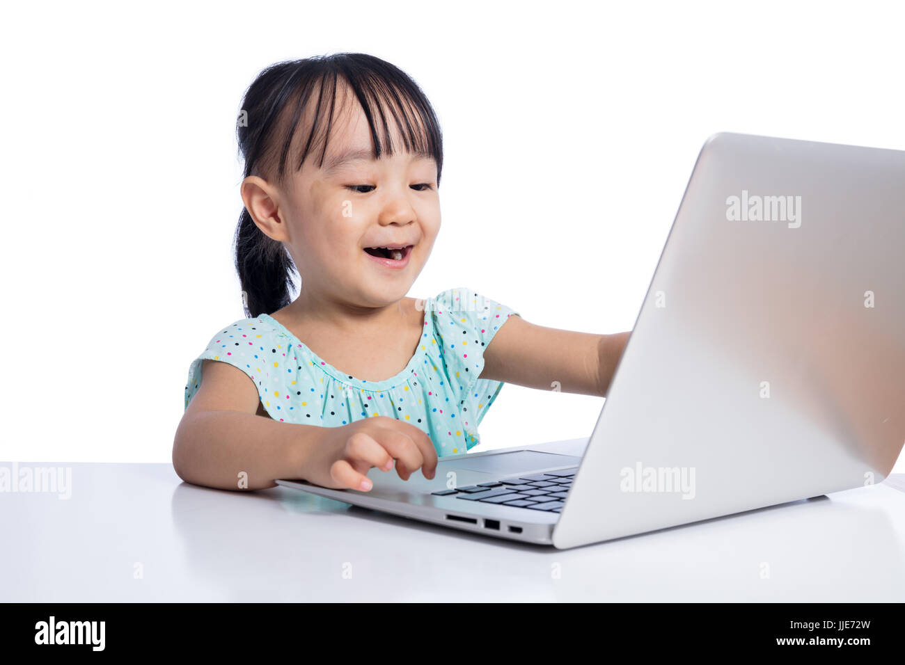 Asian Chinese little girl playing with laptop in isolated white ...