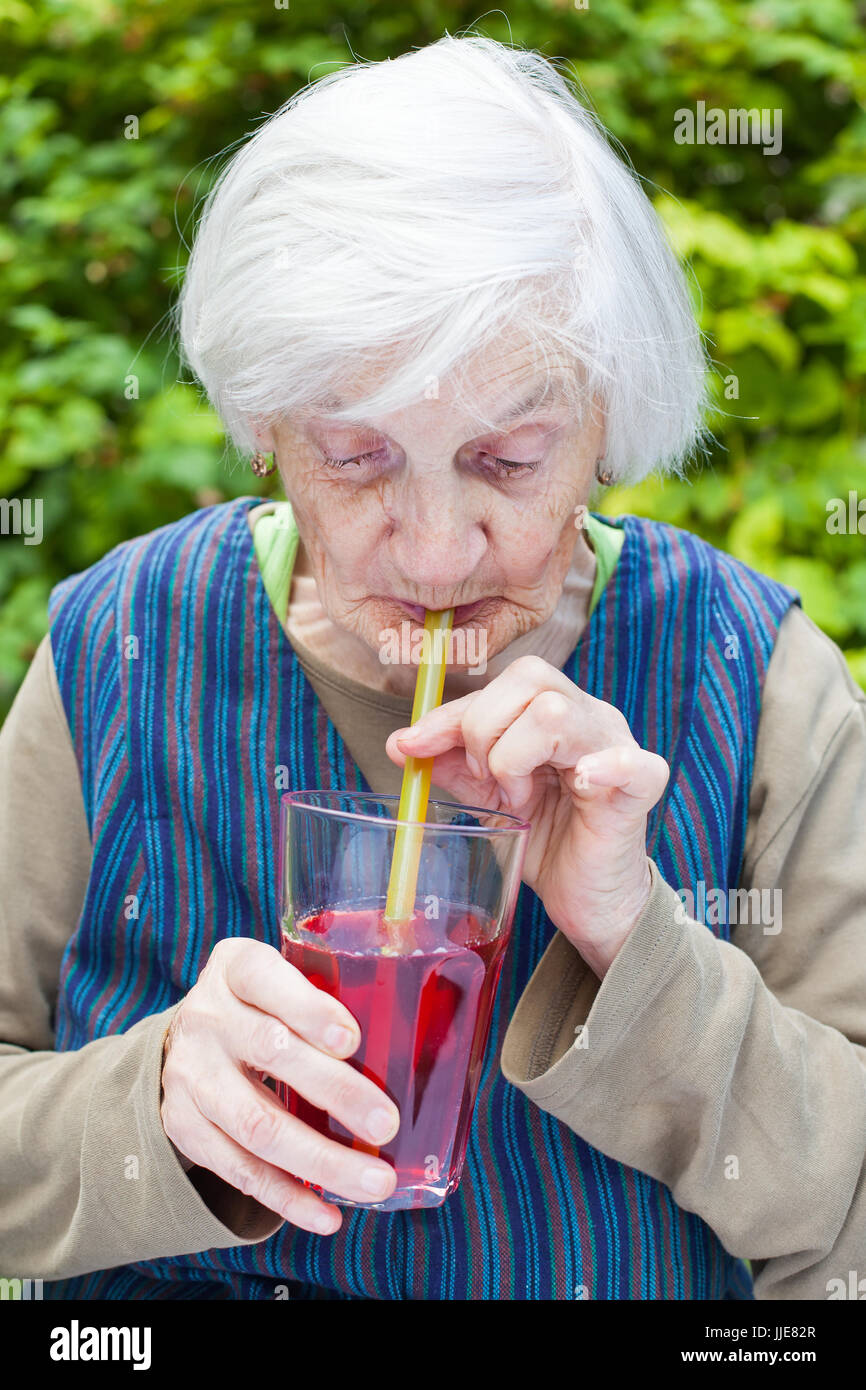 Portrait of an elderly woman with alzheimer disease drinking raspberry ...