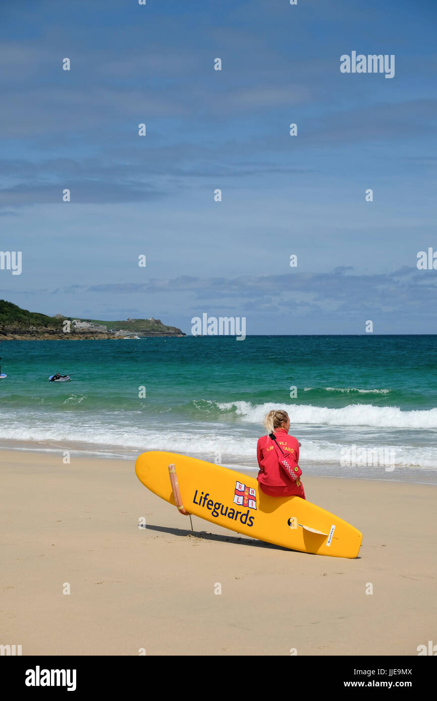 young female lifeguard watching the sea on the beach at Carbis Bay ...