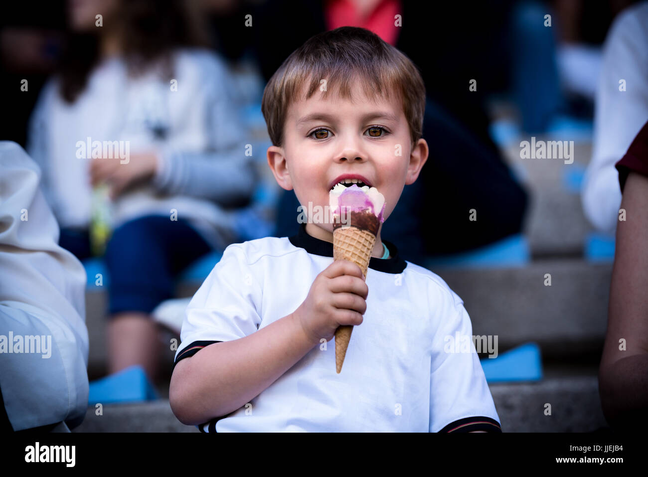 Cute child in the stadium licking an ice cream Stock Photo - Alamy