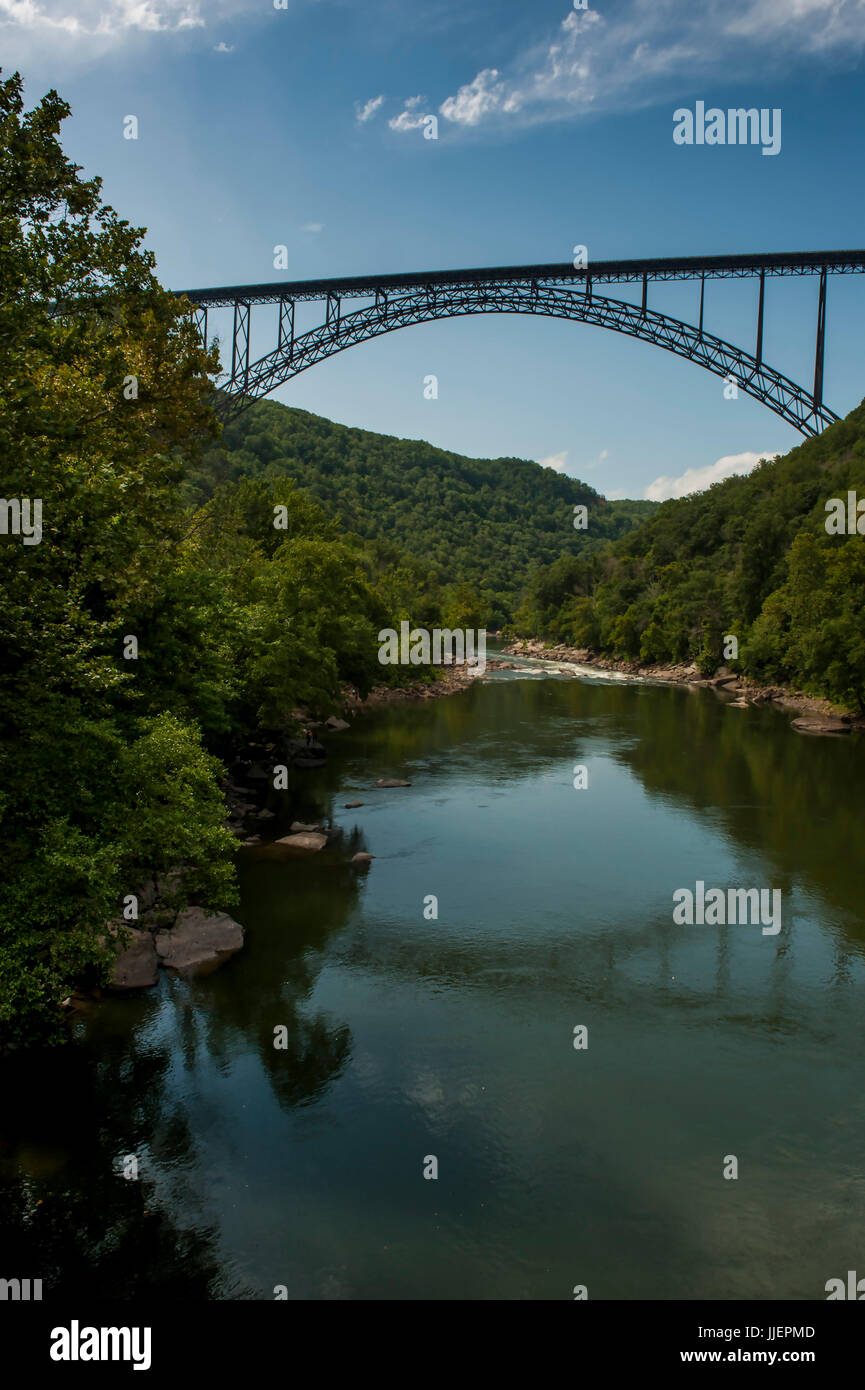 A large steel bridge arches over the New River Gorge and the New River ...