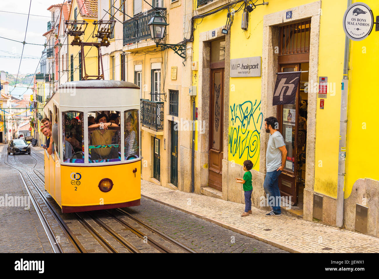 Lisbon tram street, view of a father and son watching a tram carrying ...