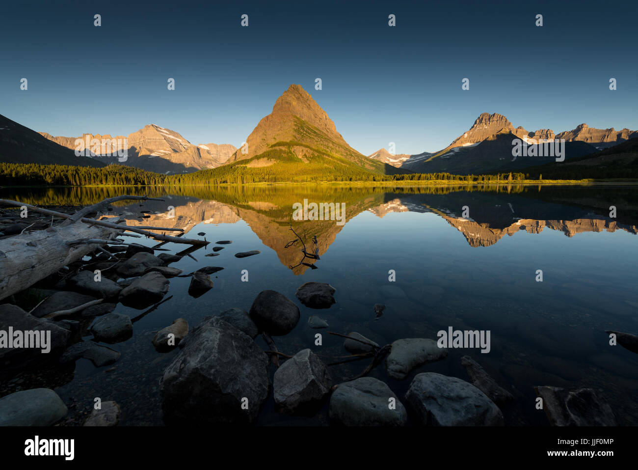 Lake reflecting gorgeous mountains and peaks washed in golden sunlight ...