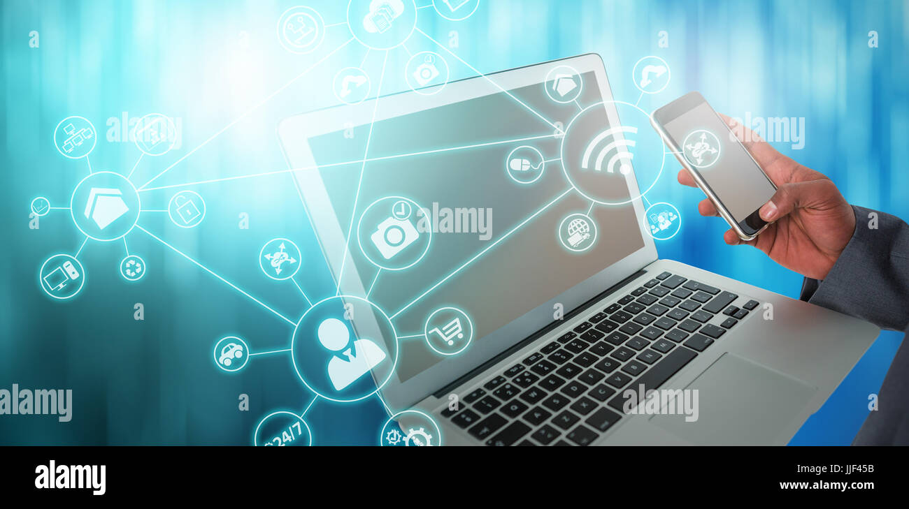 Businessman using laptop and mobile phone against glowing background ...