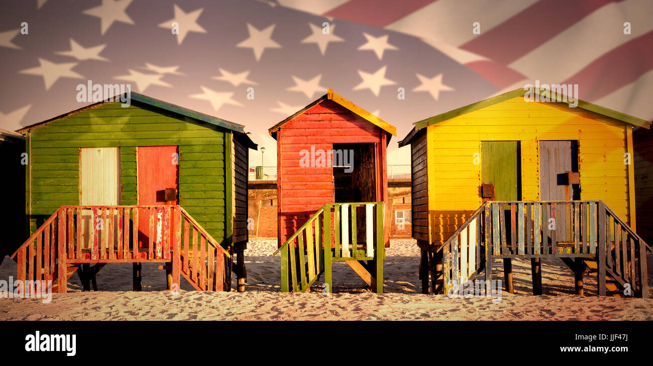 Close up of the us flag against multi colored huts on sand against ...