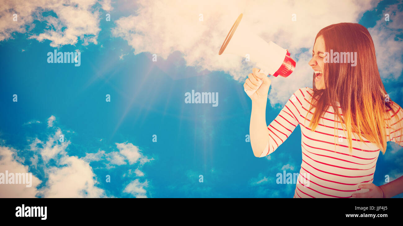 Young woman yelling with megaphone against view of beautiful sky and ...