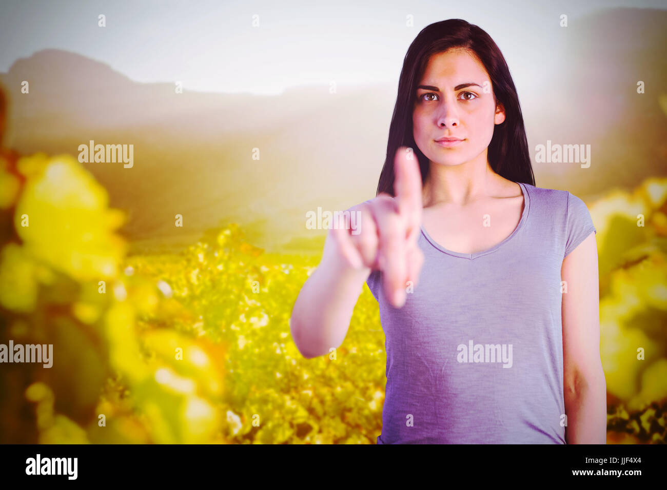 Portrait of young woman pointing against greenness field of grapevine ...
