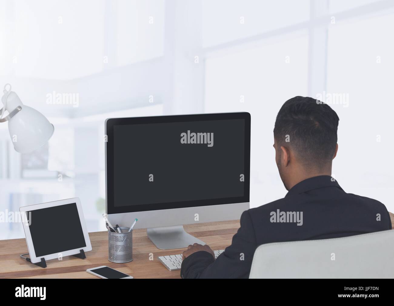 Digital composite of Businessman on computer in large bright office ...