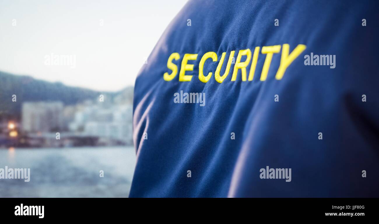 Digital composite of Back of security guard jacket against blurry ...