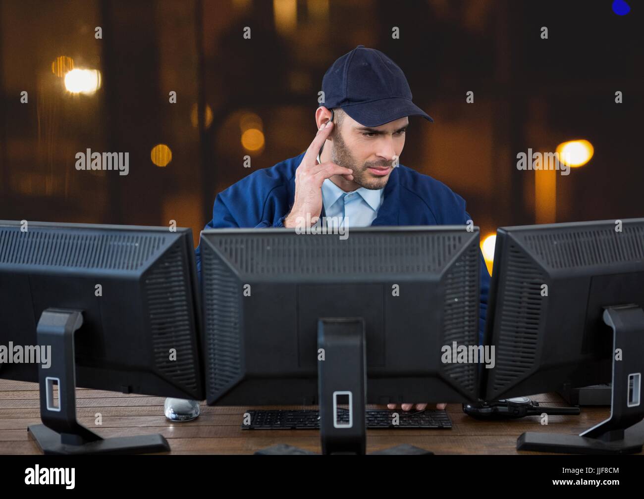 Digital composite of security guard behind the screens in the office at ...