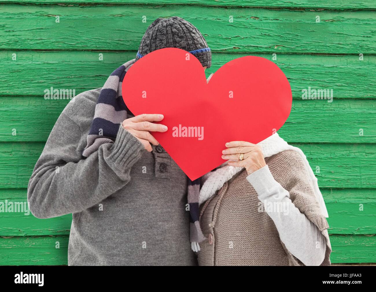 Digital composite of couple behind the heart with green wood background ...