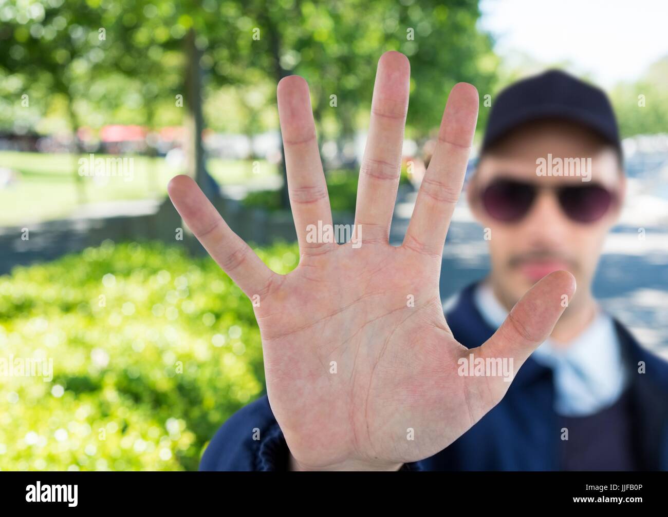 Digital composite of blurred security guard saying stop with his hand ...