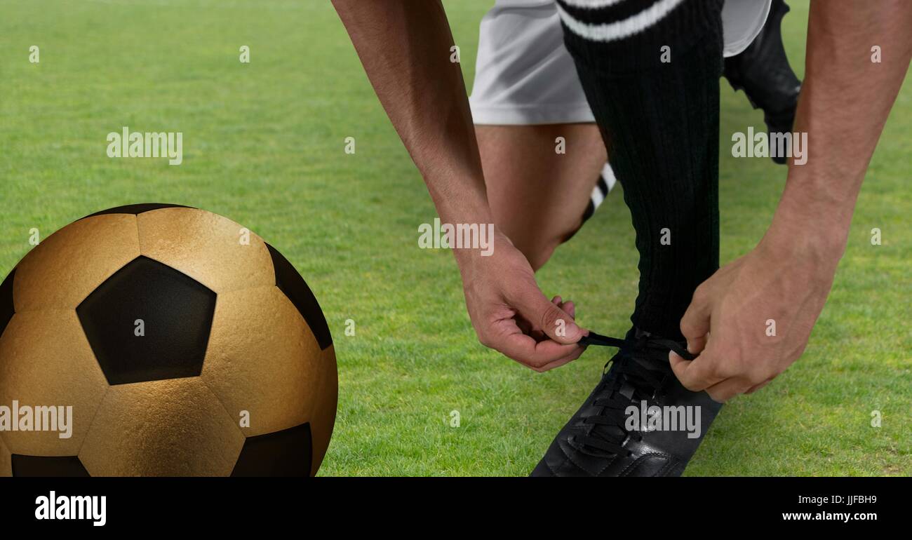 Digital composite of soccer player tying his shoes with golden ball ...