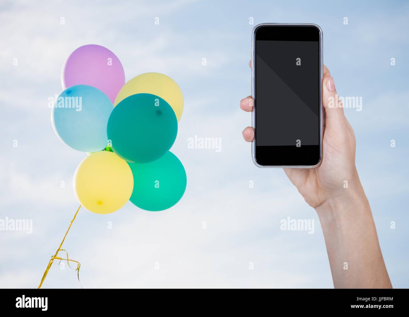 Digital composite of Hand with phone against sunny sky and balloons ...