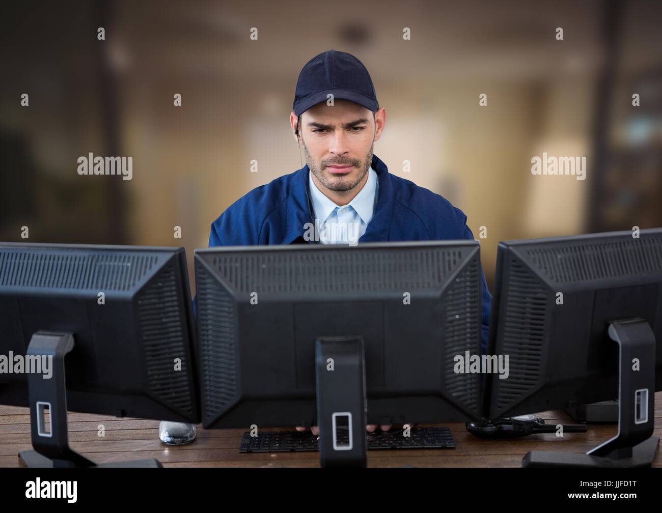 Digital composite of security guard looking the screens in a blurred ...