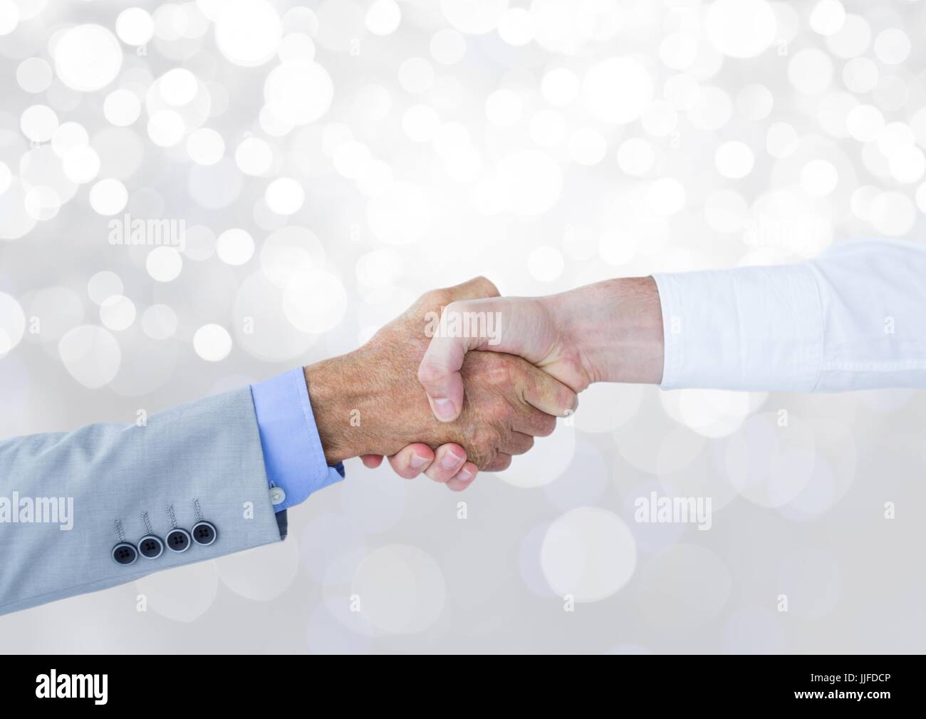 Digital composite of Hands shaking with sparkling light bokeh ...