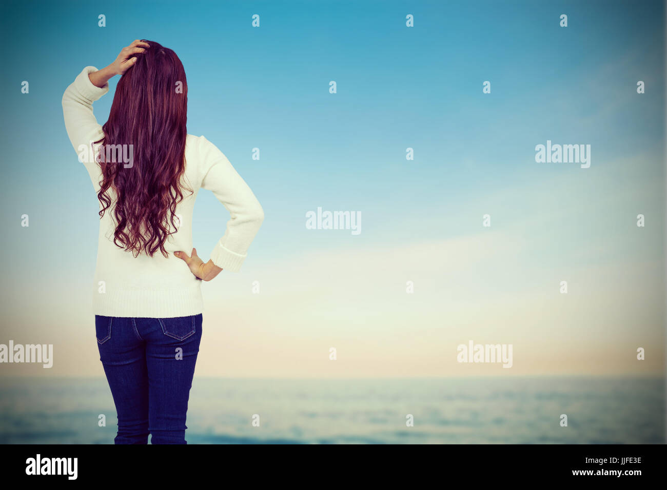 Full length rear view of brunette with hand in hair against beautiful ...