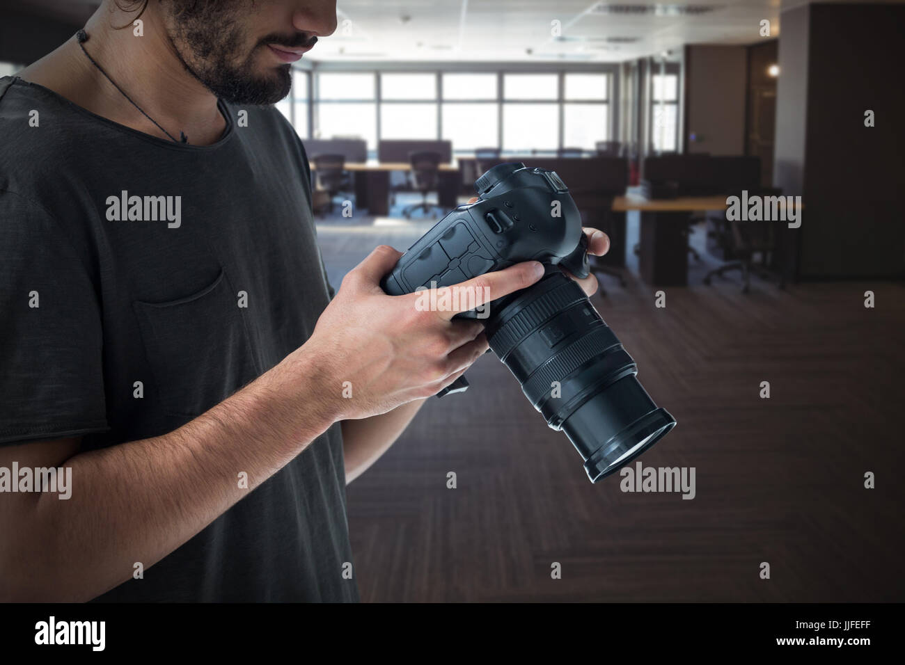 Young photographer operating digital camera against table and empty ...