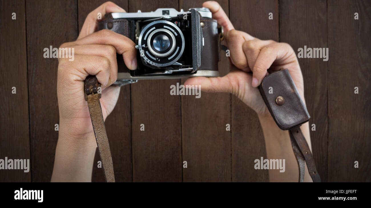 Cropped image of hands holding camera against wood panelling Stock ...