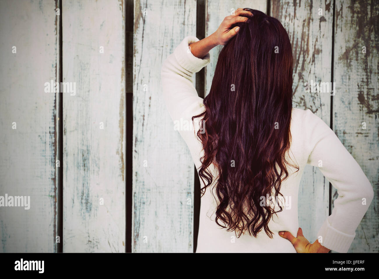 Full length rear view of brunette with hand in hair against wood ...