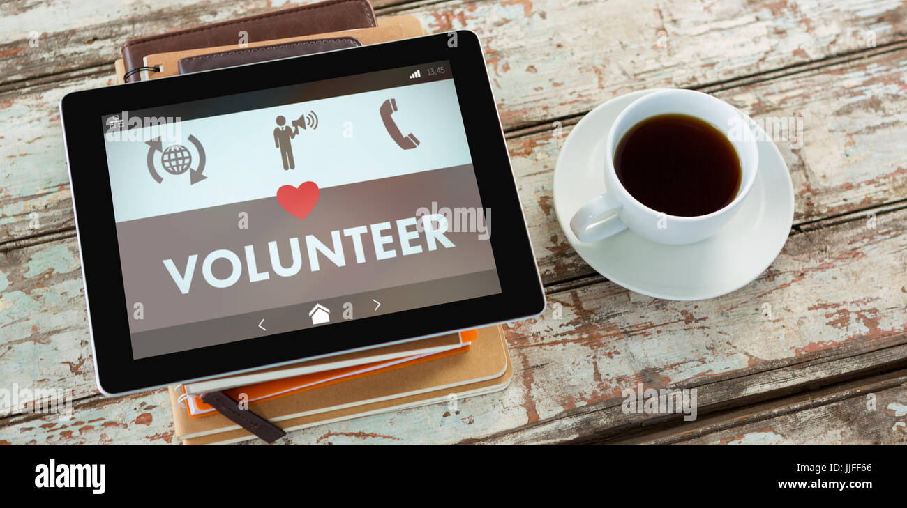 Volunteer text with various icons on screen against tablet and coffee ...