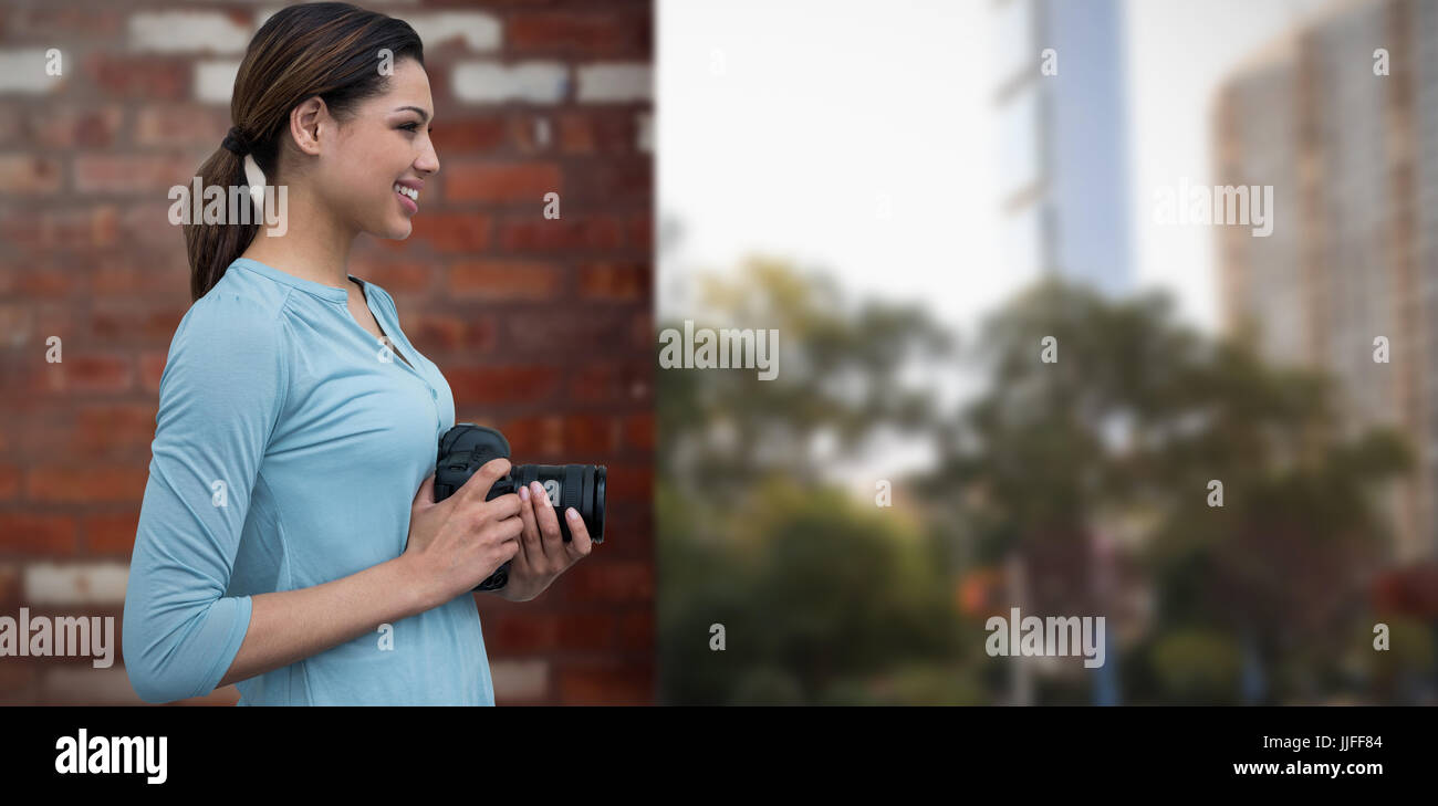 Side view of female photographer holding digital camera against wall of ...