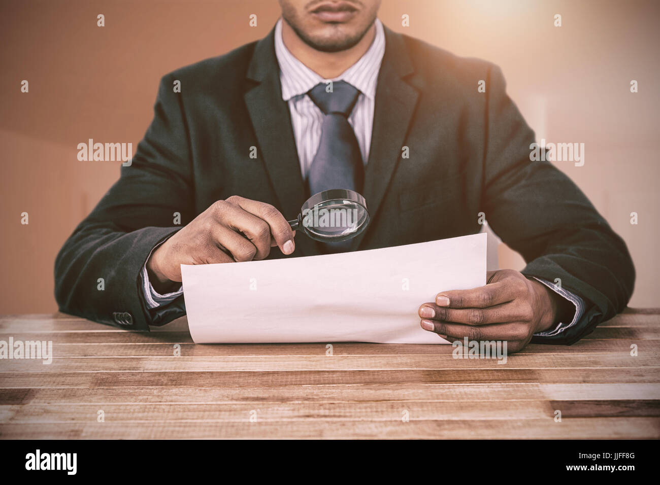 Businessman looking at document through magnifying glass against bright ...